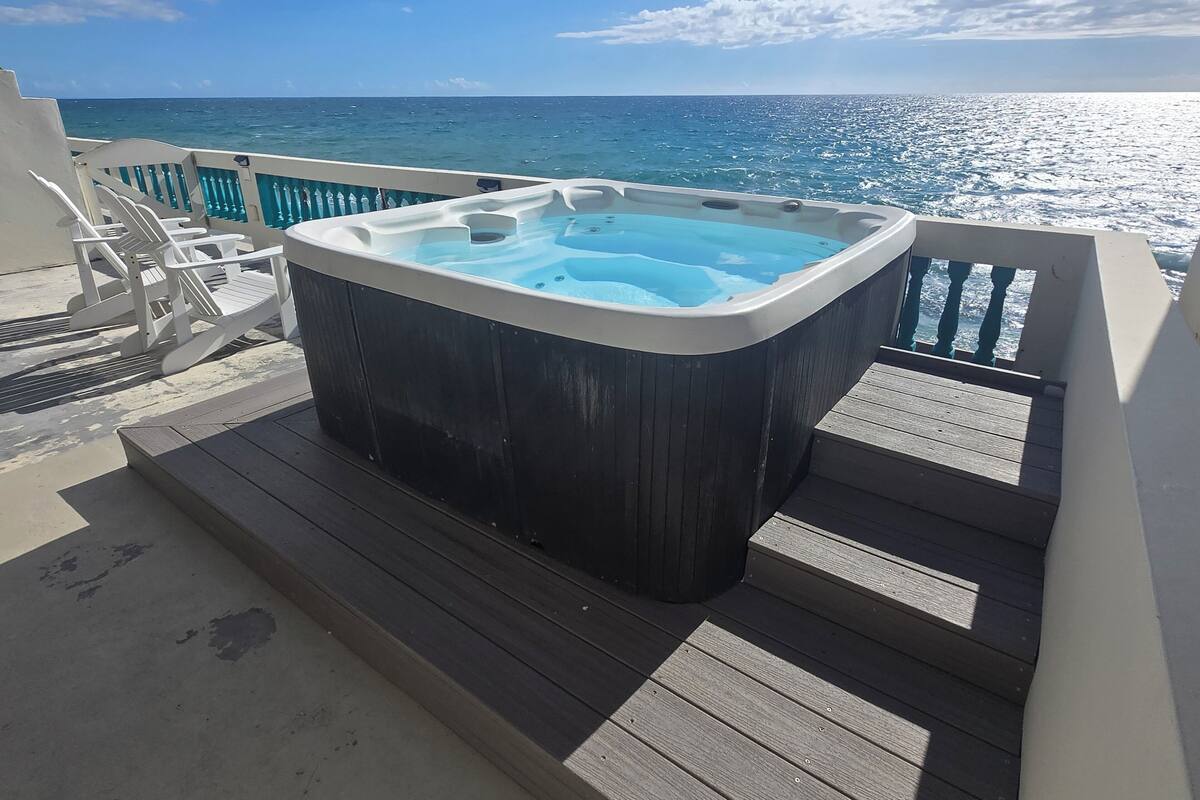 Uma banheira de hidromassagem em um deck de madeira com vista para o oceano.