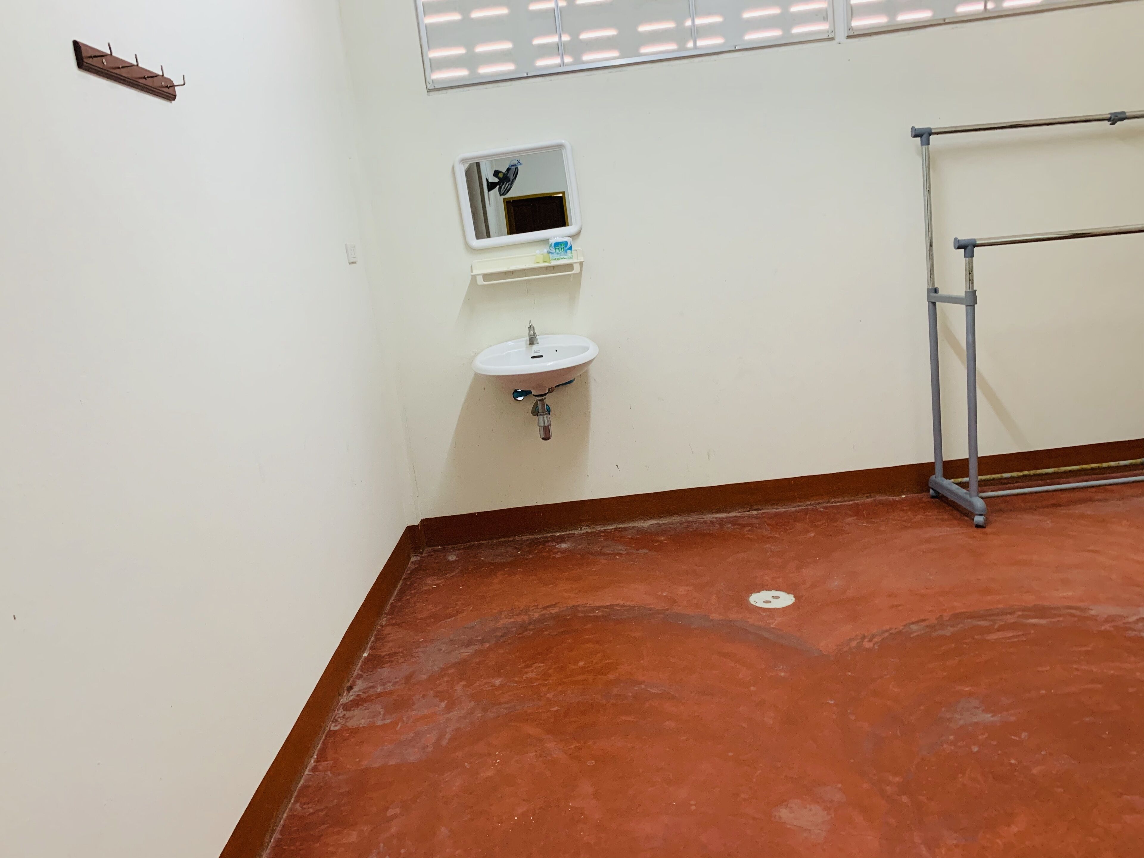 Casa de banho com uma pia branca, um espelho e um porta-toalhas.