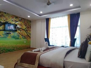Quarto de hotel com cama, televisão fixada na parede e janela com cortinas.