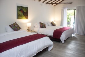 Quarto de hotel com duas camas, um quadro na parede e uma varanda com cortinas.