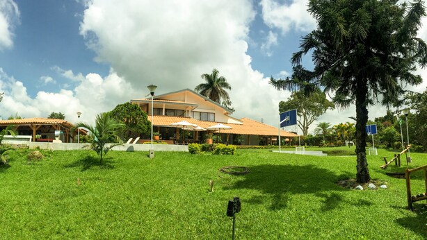 Um hotel com um gramado amplo, palmeiras e um edifício com telhado de azulejos.