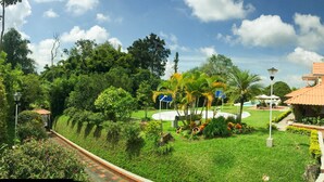 Um pátio com um piso de azulejos, área de estar coberta e vegetação exuberante.