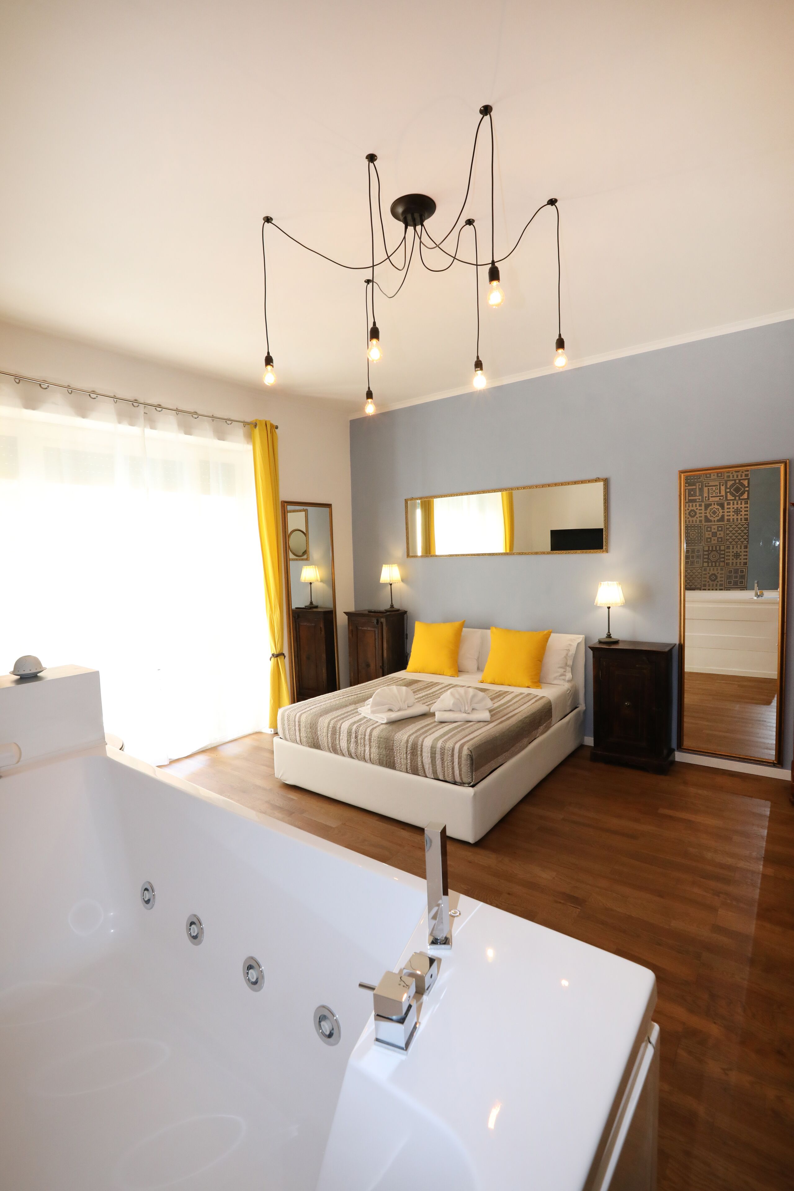 Quarto moderno com uma cama grande, banheira e um candelabro.