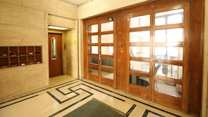 Um hall com uma grande porta de madeira, um balcão de recepção e um piso estampado.