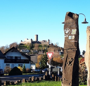 Um castelo medieval numa colina, com uma escultura moderna em primeiro plano.