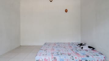 Um quarto pequeno e vazio com uma cama e um travesseiro.