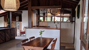 Uma cozinha ampla com mesa de jantar de madeira, luminária pendente e painel de parede em tijolos.