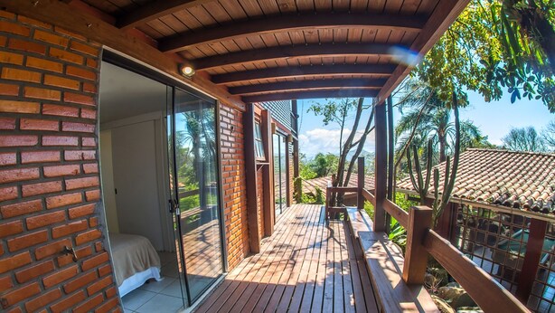 Um deck de madeira com uma porta de vidro que dá para um quarto, cercado por um cercado de madeira e cactos.