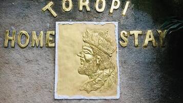 Placa com os dizeres 'TOROPI HOME STAY' e um relevo dourado do perfil de uma pessoa.