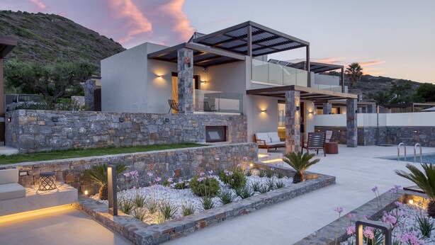 Uma casa moderna com fachada de pedra, área de estar externa e piscina.