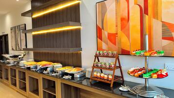 Disposição de buffet com diversos alimentos e uma pintura abstrata decorativa na parede.