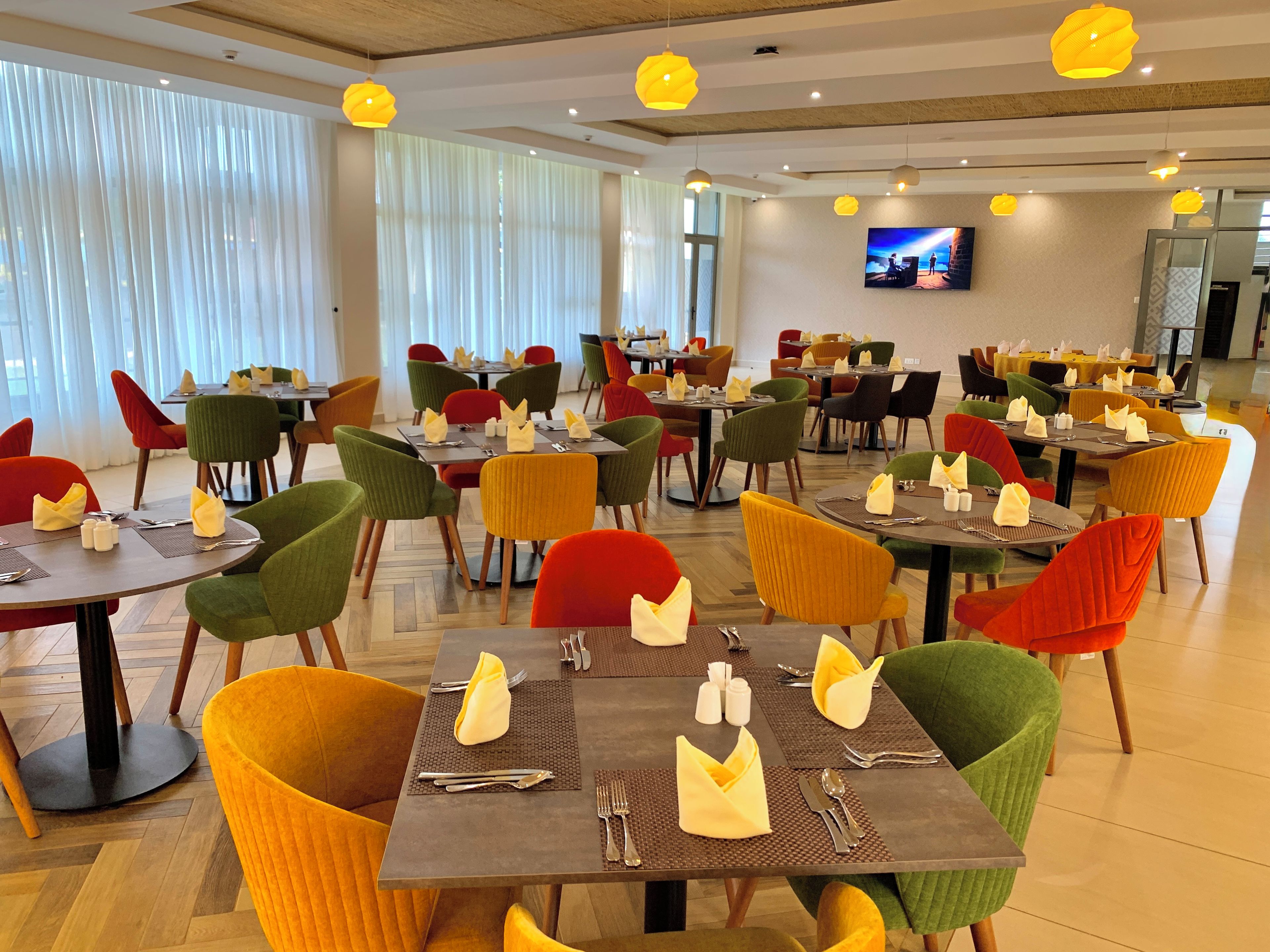 Uma sala de jantar com várias mesas e cadeiras, cada conjunto com talheres e guardanapos.