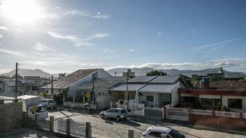 Rua residencial com casas, carros e céu claro.