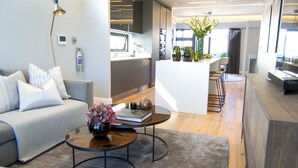 Uma sala de estar moderna com sofá, mesa de centro e cozinha ao fundo.