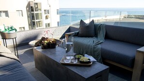 Uma área de estar moderna ao ar livre, com um sofá, uma mesa de centro e vista para o oceano.