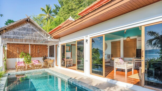 Uma casa moderna com piscina, deck de madeira e grandes portas de vidro que dão para um espaço de pátio.