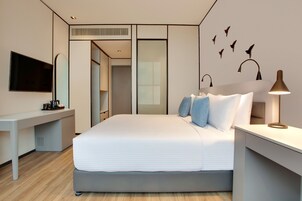 Quarto moderno com cama, mesas de cabeceira, escrivaninha, televisão e parede com adesivos de pássaros.