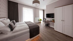 Quarto de hotel moderno com uma cama, uma escrivaninha, uma televisão e um guarda-roupa.