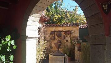 Um arco de pedra ao ar livre com uma parede de pedra rústica, um vaso de barro grande e plantas em vasos.