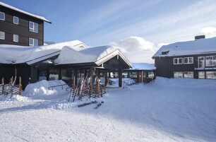 Um edifício coberto de neve com equipamento de esqui à frente.