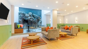 Uma sala de estar moderna com um grande mural na parede, assentos confortáveis e uma TV de tela plana.