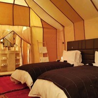 Um quarto tipo tenda com duas camas, um guarda-roupa e um espelho.