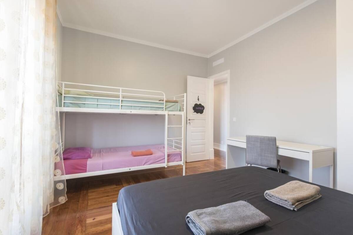 Quarto com uma cama de solteiro, uma escrivaninha e uma cadeira.