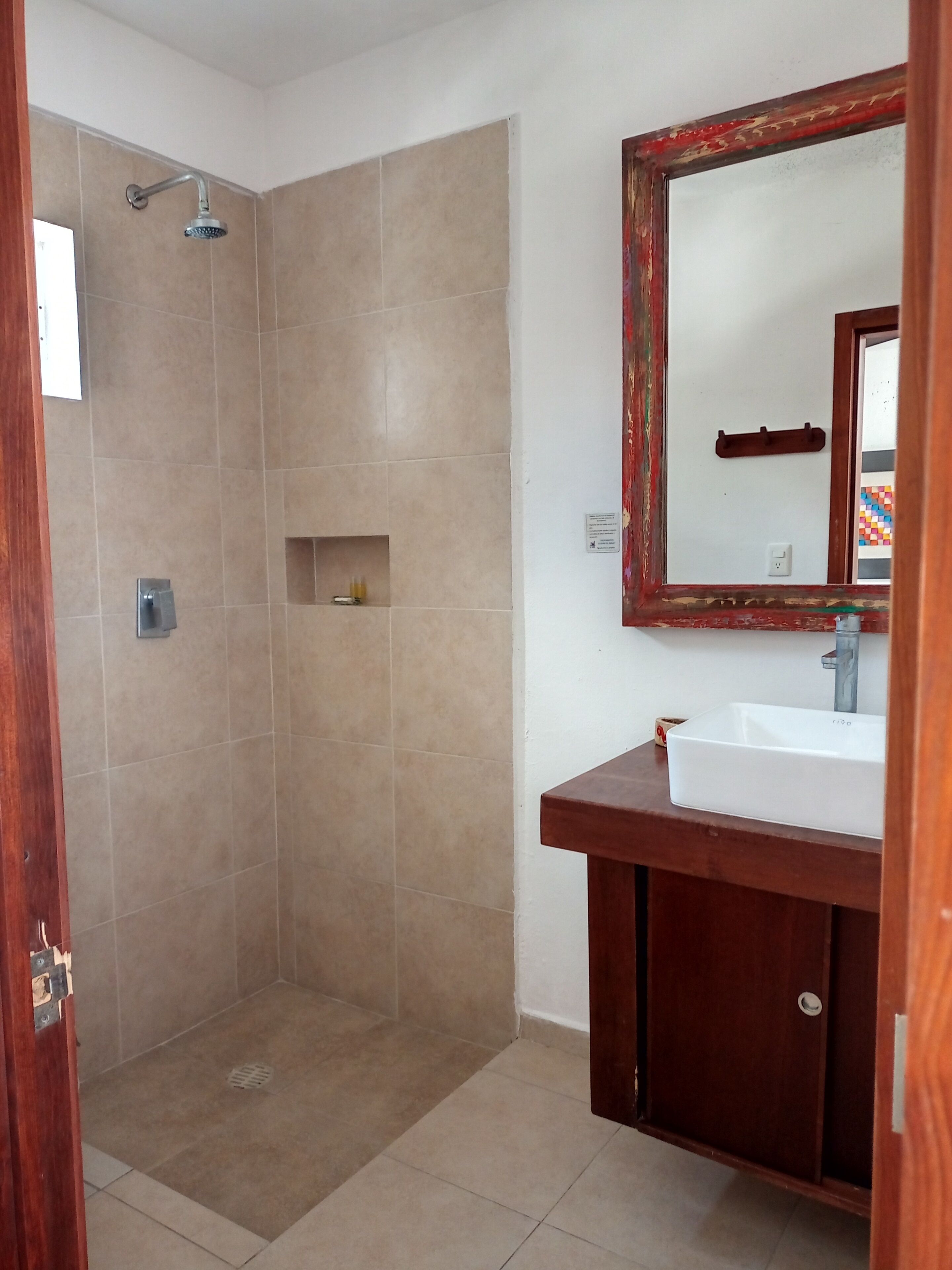 Casa de banho com chuveiro, lavatório e espelho.