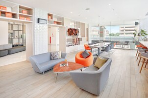 Um hall de hotel moderno com área de estar, uma mesa de centro e uma estante de livros.