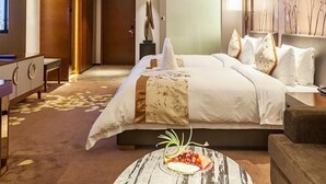 Quarto de hotel moderno com uma cama grande, uma escrivaninha e um espaço de estar.