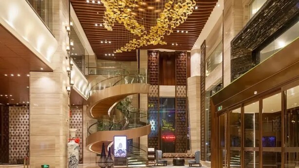 Um hall de hotel moderno com uma escada espiral, um lustre grande e uma área de estar.