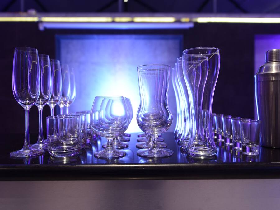 Uma área de bar com vários copos e um coqueteleira.