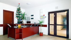 Uma área de recepção com uma mesa de madeira, um pinheiro de Natal e um vaso com planta.