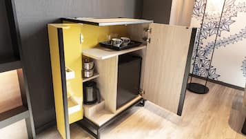 Uma cozinha compacta com um armário amarelo, bancada preta e uma pequena prateleira com utensílios de cozinha.