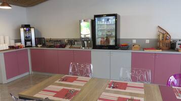 Cozinha moderna com frigorífico, máquina de café e micro-ondas. Armários rosa e uma mesa de jantar posta com talheres.