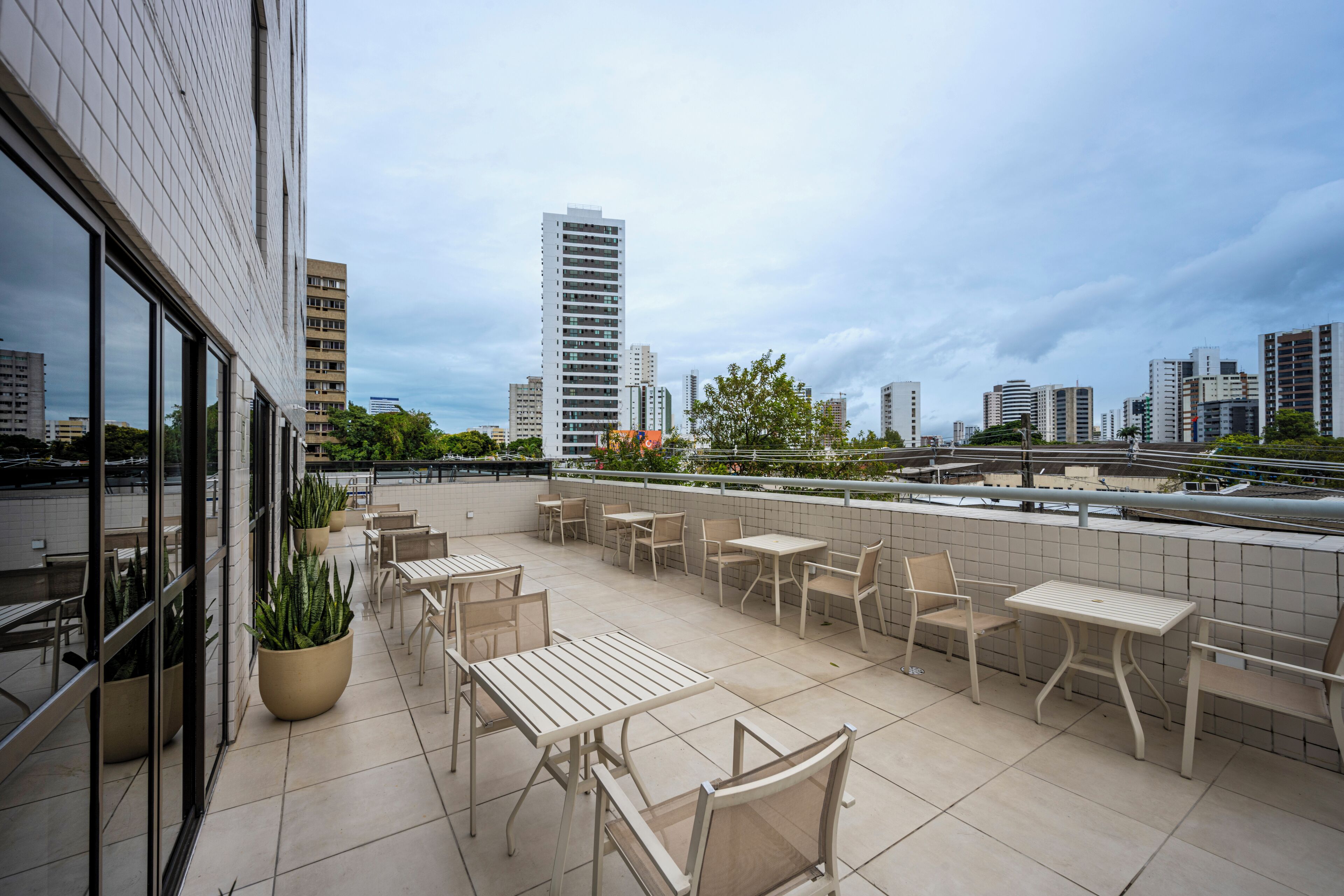 Terraço no telhado com área de estar externa e plantas em vasos.