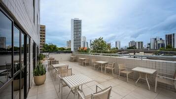Terraço no telhado com área de estar externa e plantas em vasos.