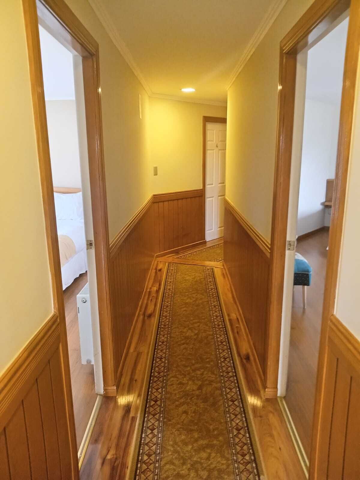Um corredor com painéis de madeira e carpete estampado.