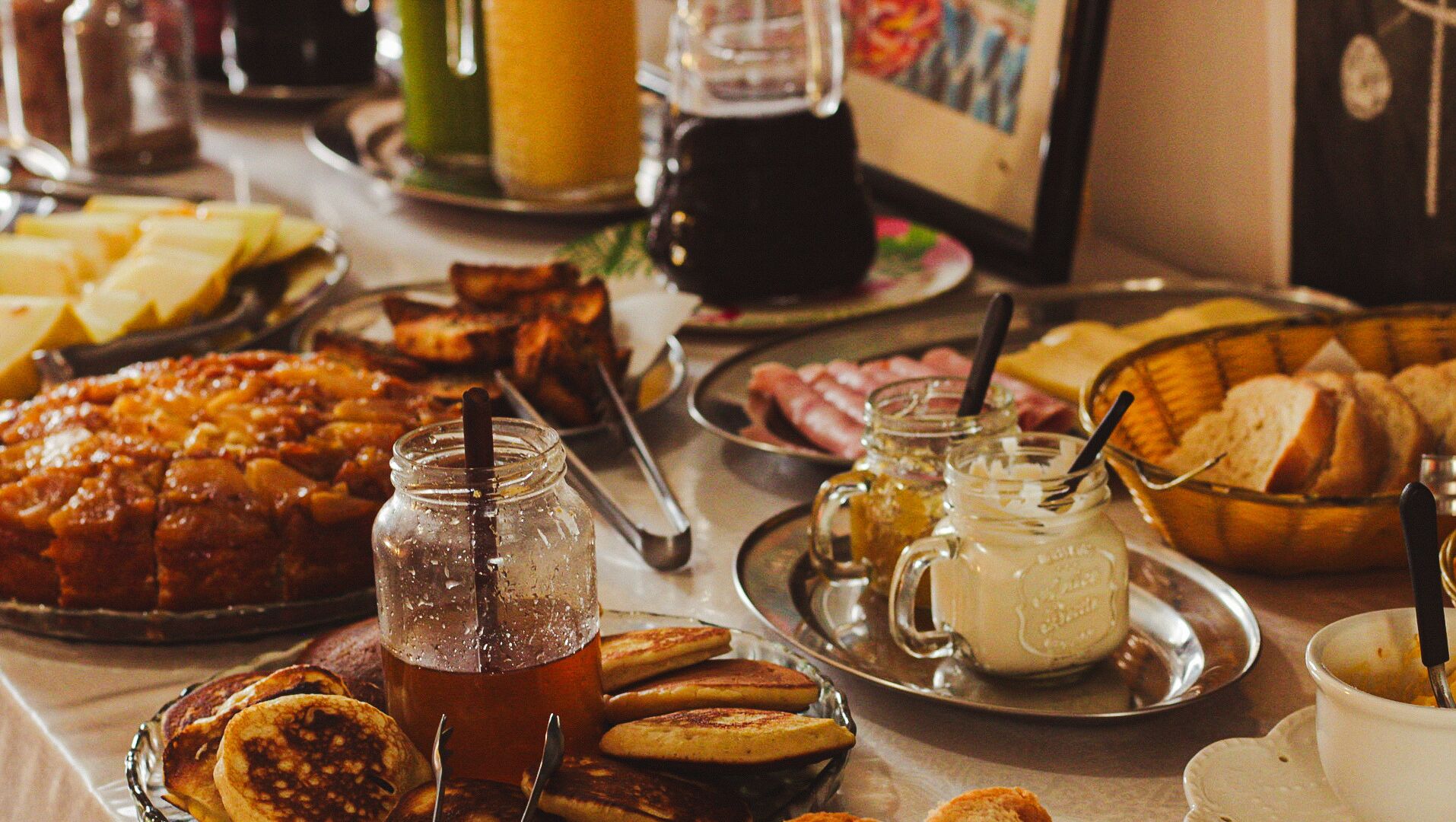 Um buffet de café da manhã com diversos alimentos, bebidas e utensílios.