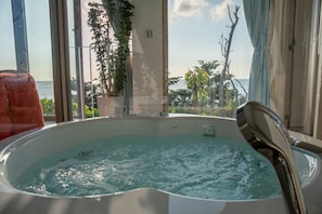 Banheira de hidromassagem com vista para o oceano através de amplas janelas.