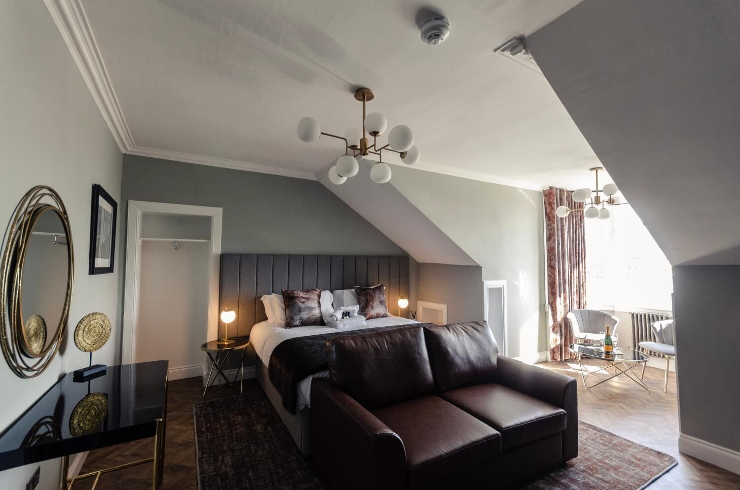 Quarto moderno com uma cama grande, um sofá de couro, um ventilador de teto e uma varanda com cadeiras.