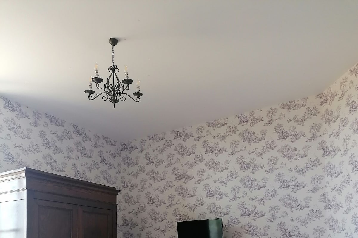 Um quarto com uma cama, um guarda-roupa de madeira, uma televisão sobre a lareira e uma lareira.