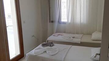Quarto com duas camas, janela com cortinas leves e porta que dá para o exterior.