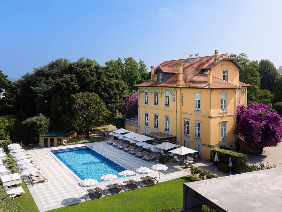 Um edifício grande com piscina, espreguiçadeiras e guarda-sóis.