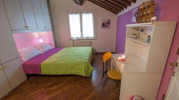 Quarto com cama, uma cadeira, escrivaninha e prateleira com potes.