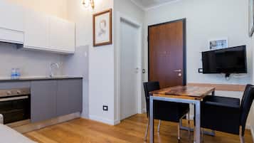 Cozinha moderna com armários cinza, forno embutido e mesa de jantar de madeira com cadeiras pretas.