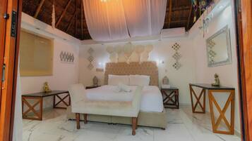Quarto com cama, duas mesas de cabeceira, uma luminária no teto e uma parede decorada.