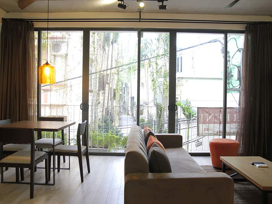 Uma sala de estar moderna com sofá, mesa de jantar com cadeiras e um grande painel de vidro deslizante que dá para uma área externa.