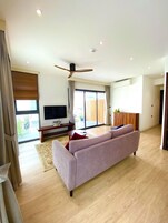 Uma sala de estar moderna com sofá, televisão e ventoinha de teto.