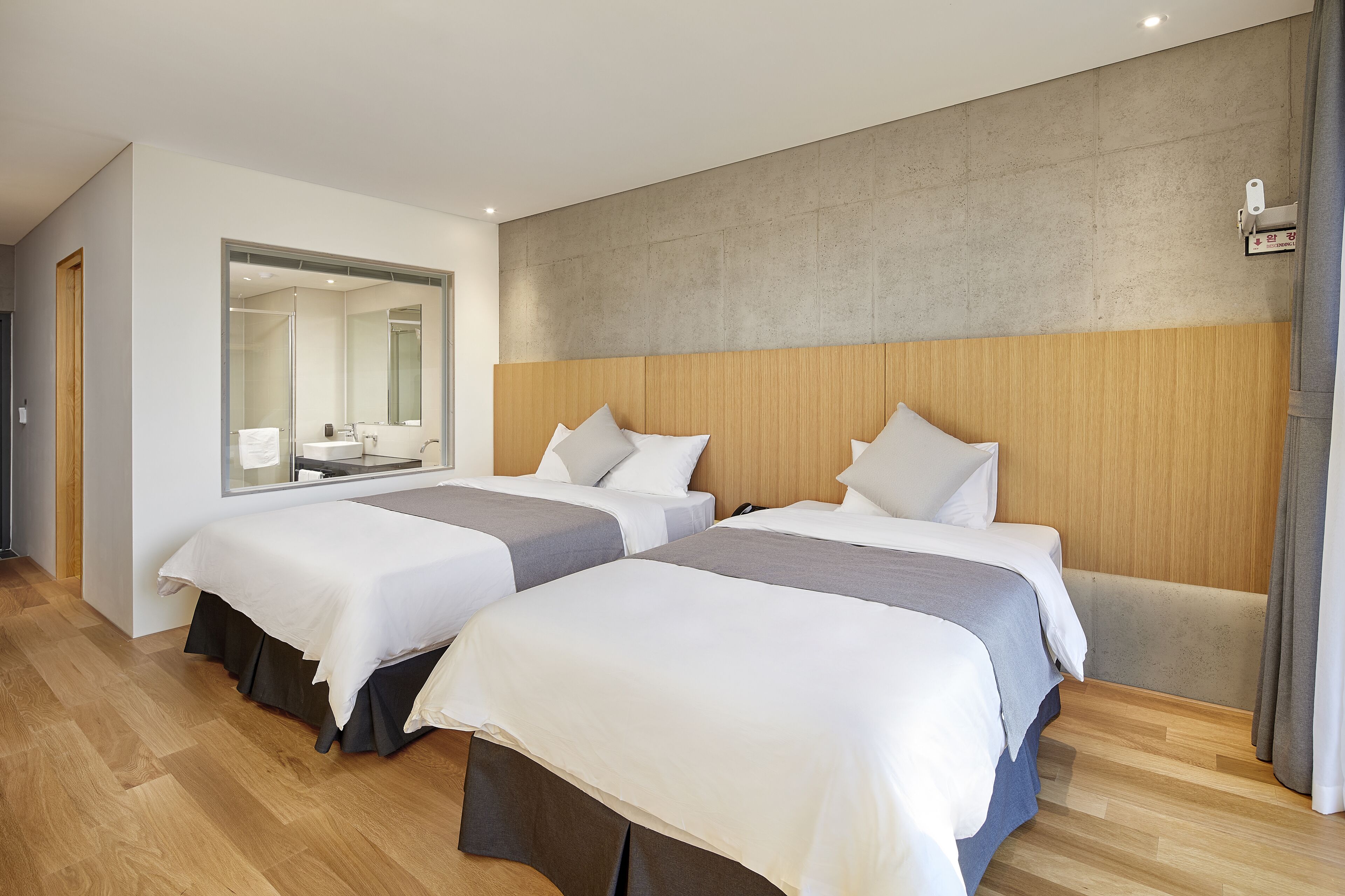 Quarto de hotel com duas camas, um espelho grande e uma cabeceira de madeira.